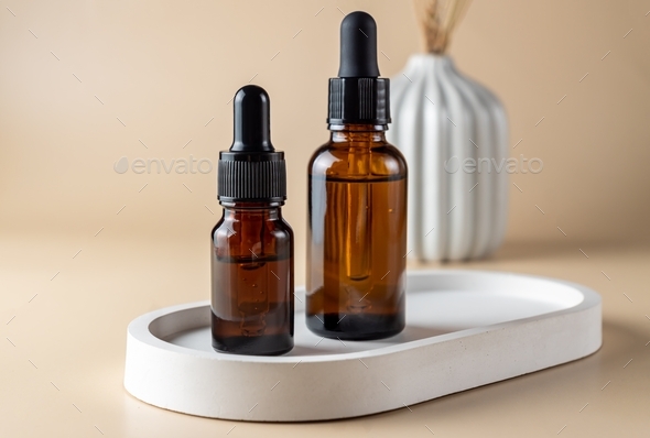 Set of brown glass bottles with essential oil on a beige background ...