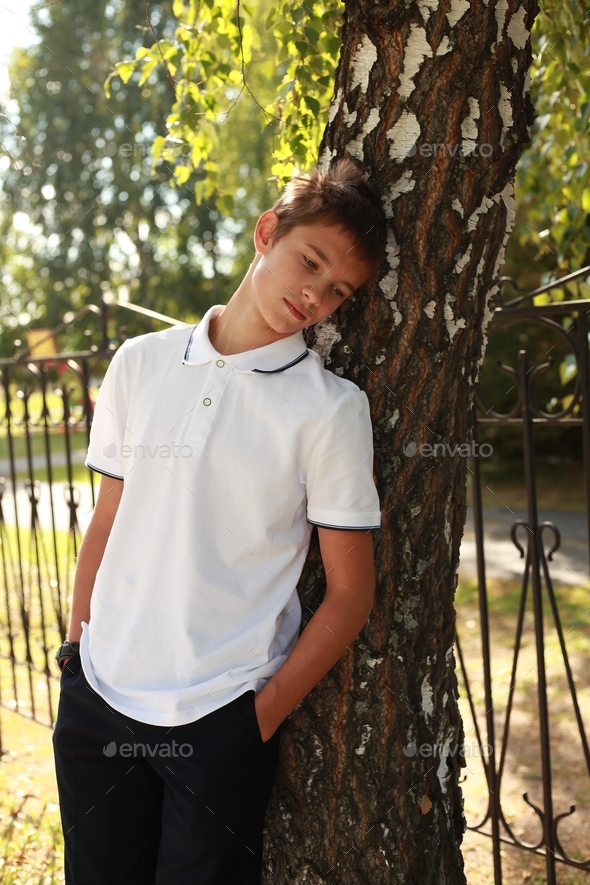 The guy is leaning against a tree with a thoughtful look. Stock Photo ...