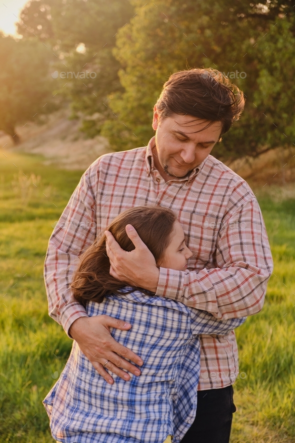 Smiling little girl hugging her father outside Stock Photo by InnaVlasova