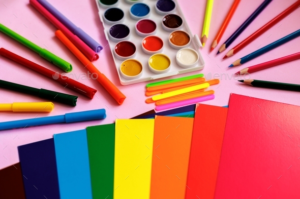 Bright and colorful objects for creativity lie on a pink and purple ...