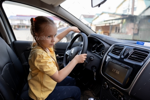 A cute 7-year-old girl is driving a car in the parking lot. Stock Photo ...