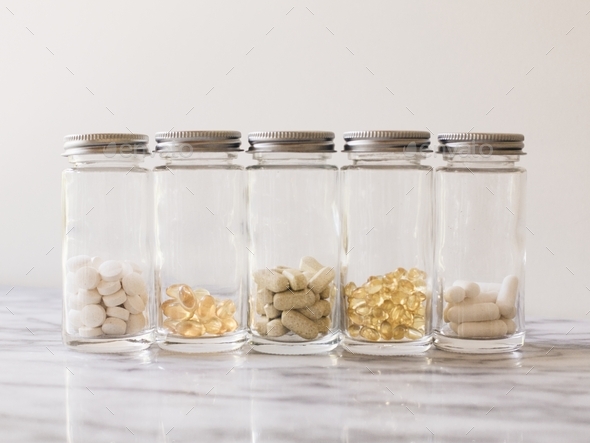 Vitamin jars hold a variety of supplements on a marble counter Stock ...