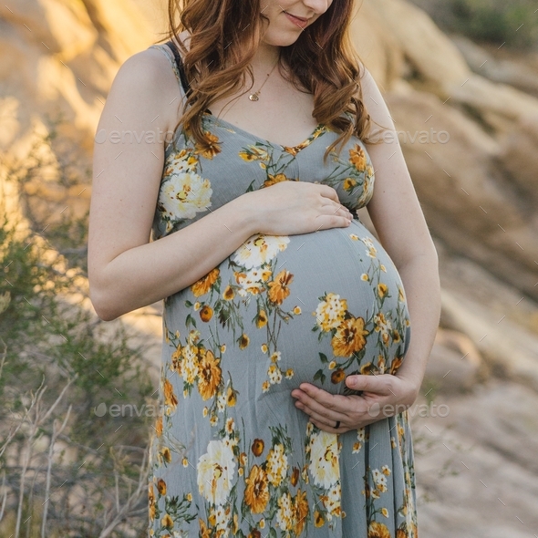 Young mom holds her big baby belly in her last trimester of pregnancy ...