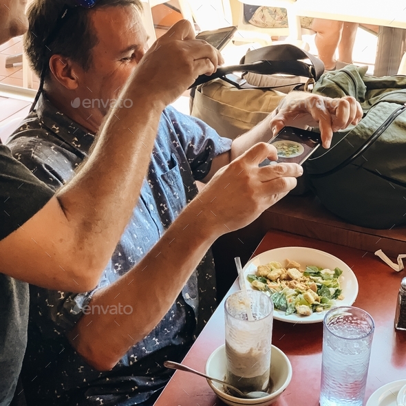 Food photography using mobile phones with friends while eating at a ...