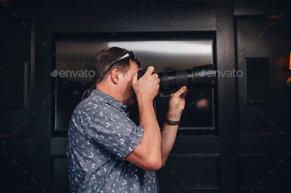 Man holding and looking into a camera with a stinkin' long lens in a ...