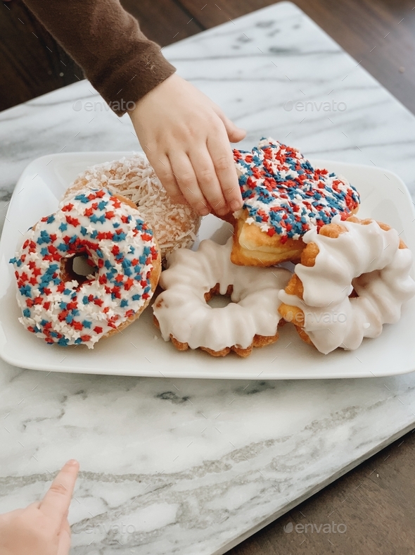 Kids pointing and reaching for doughnuts that are decorated in red ...