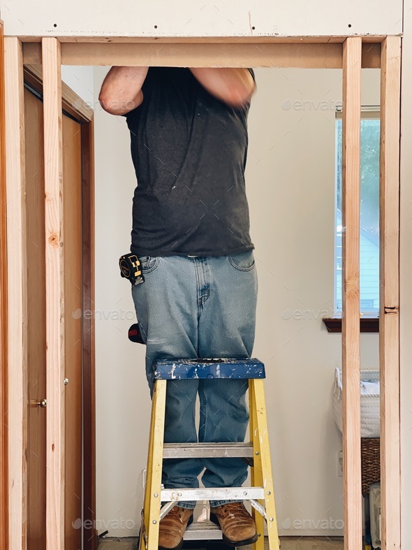 Construction worker man framing a doorway in a home Stock Photo by debbalba