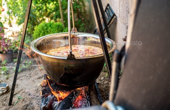 Pot with vegetables cauldron over open fire, preparing stew soup on ...