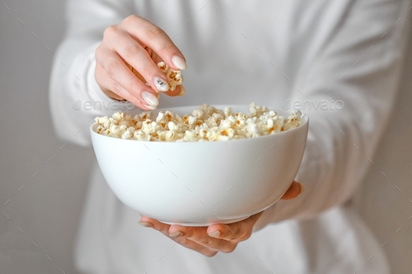 Making popcorn at home, a teenager girl holding a big cup with ready ...