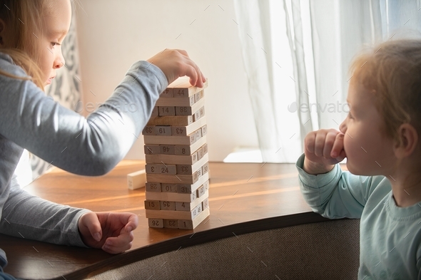 Children at home play board game with Jenga sticks Stock Photo by olgar23