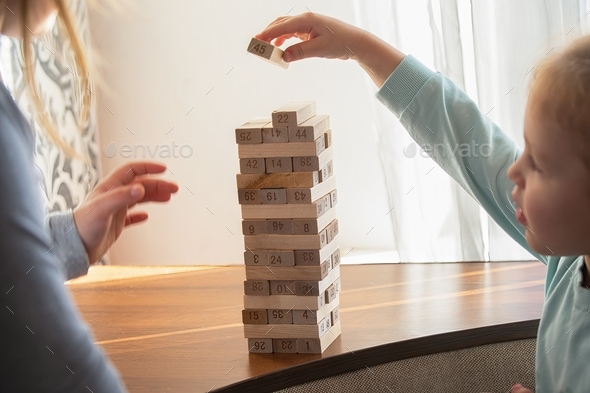 Children at home play board game with Jenga sticks Stock Photo by olgar23