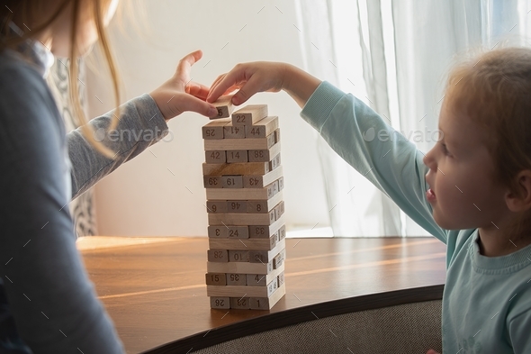 Children at home play board game with Jenga sticks Stock Photo by olgar23