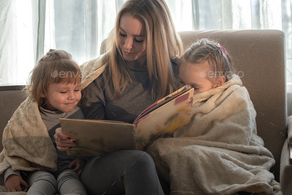family spends leisure time at home reading a book Stock Photo by olgar23