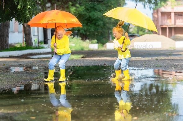 two sisters on an active and fun walk through the puddles in the warm ...