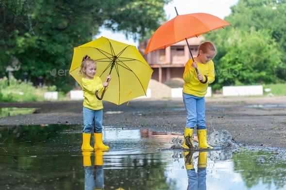 two sisters on an active and fun walk through the puddles in the warm ...