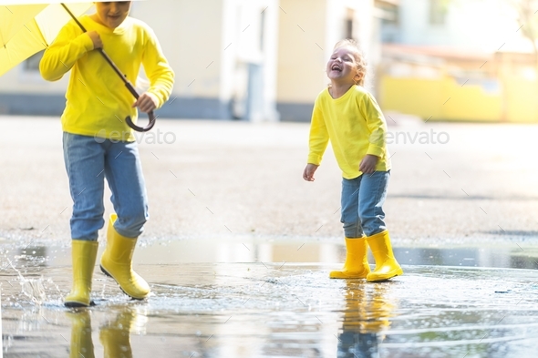 two sisters on an active and fun walk through the puddles in the warm ...
