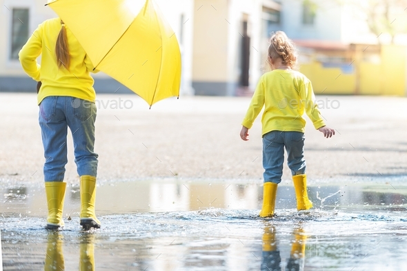 two sisters on an active and fun walk through the puddles in the warm ...