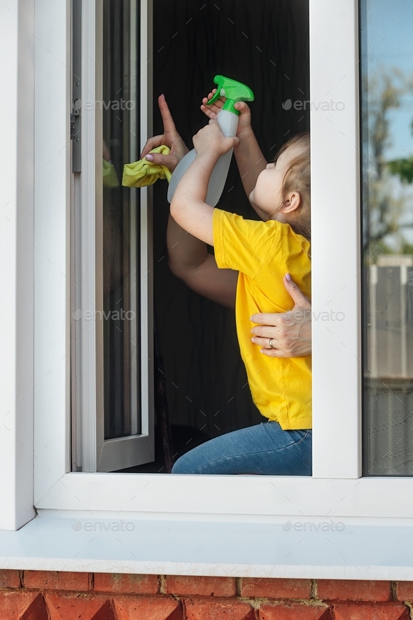 mother teaches her little daughter household chores, they clean the ...