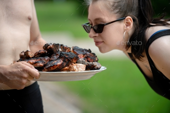 young girl have fun in front of a big dish of ready barbecue grilled ...