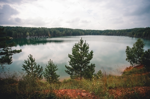 Beautiful blue lake and red clay cliffs in a forest reflecting in a ...