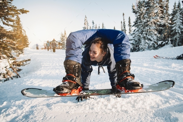 Flexible woman doing handstand on a snowboard Stock Photo by vorobeyphoto