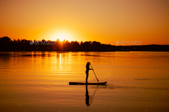 Rowing on sup board woman with oar in hands with her reflection on ...
