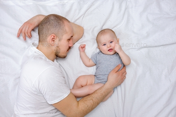 Top view a cheerful smiling baby laying on white linen with father ...