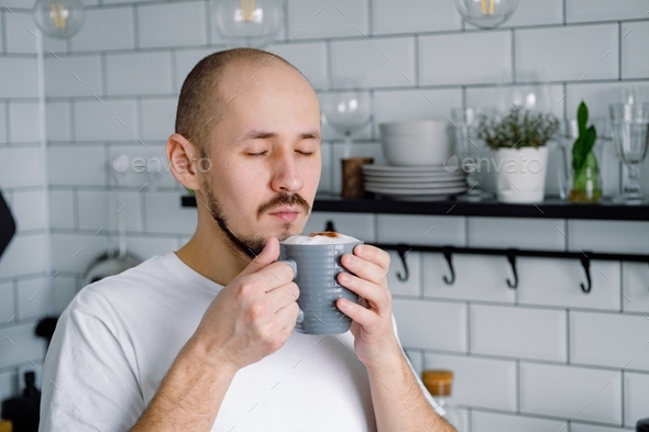 A man enjoying smelling aroma of morning coffee cappuccino. A young ...