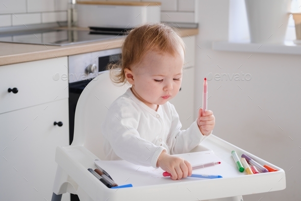 A baby toddler learning to hold a pen and drawing first picture using ...