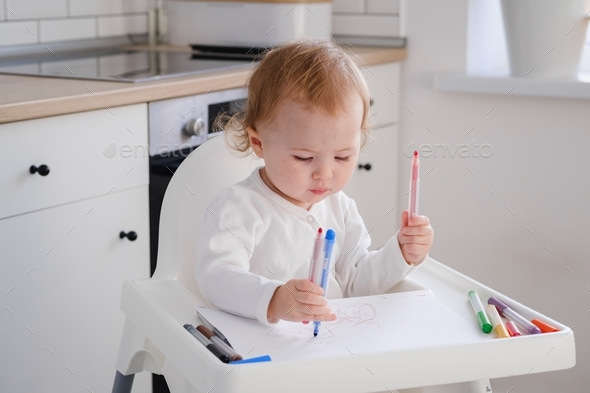 Close up of a cute baby toddler sitting drawing a picture using colored ...