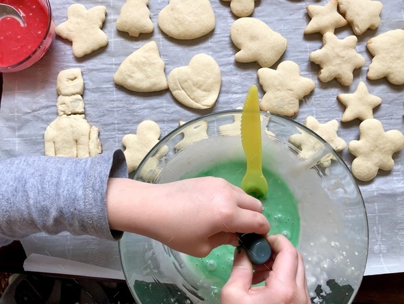 Boy putting food coloring into frosting for cookies baking at home ...