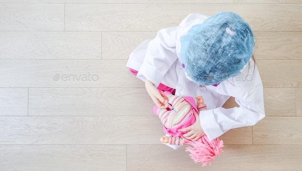 Little caucasian girl in a white coat makes an injection with a ...