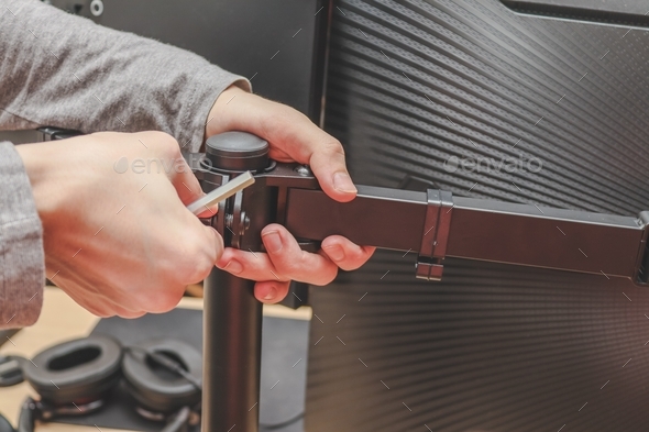 Hands of a young caucasian guy manually twists a nut on a bracket while ...