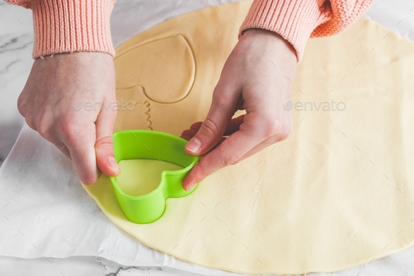 The hands of a caucasian teenage girl cut with a green plastic heart ...