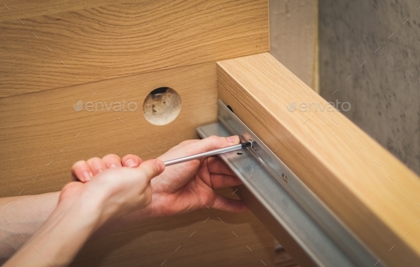 The hands of a caucasian young man are twisting a screw with a ...