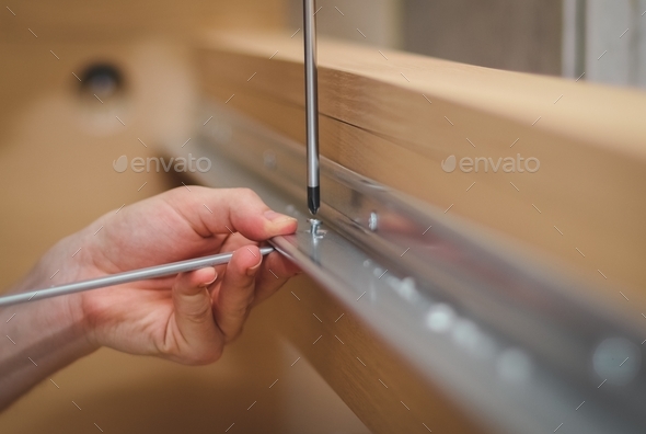 The hands of a caucasian young man twisting a screw with a screwdriver ...