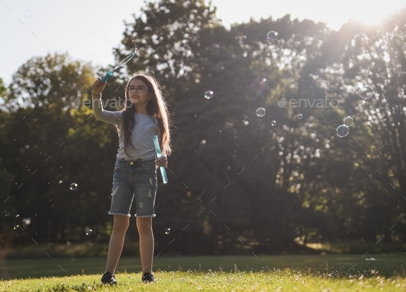 Portrait of a beautiful caucasian girl bubbles waving a wand in the ...