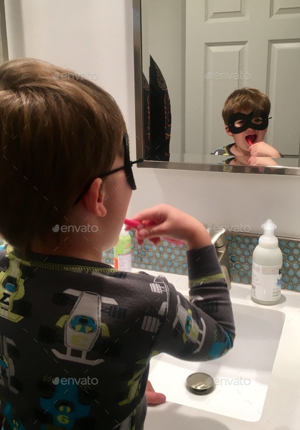 Preschool age boy brushing teeth with superhero mask on Stock Photo by ...
