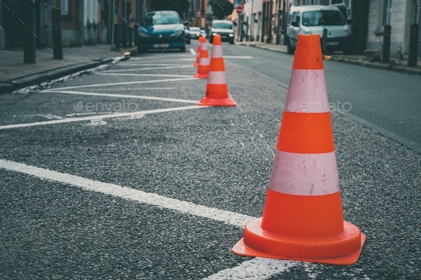 Orange and white traffic cones line up on a road with solid line ...