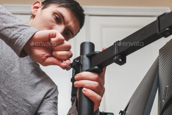 A handsome young caucasian guy manually twists a nut on a bracket while ...