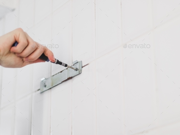 The hand of a young caucasian guy unscrew a screw to remove an old ...