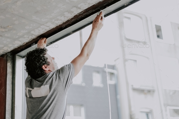 A young caucasian man repairing a window opening while and cleaning the ...