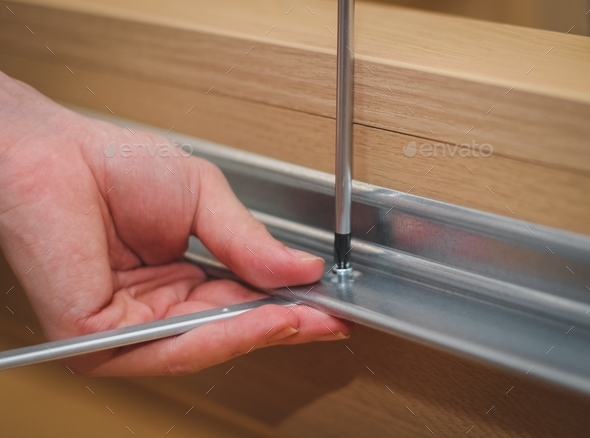 The hands of a caucasian young man twisting a screw with a screwdriver ...