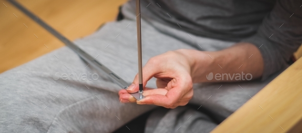 Hands of a caucasian young man twisting a screw with a screwdriver on a ...