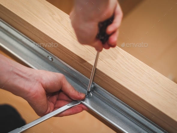 The hands of a caucasian young man twisting a screw with a screwdriver ...