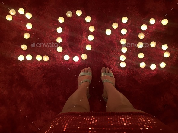 2016 sign on the carpet written with litten candles at a woman's feet ...