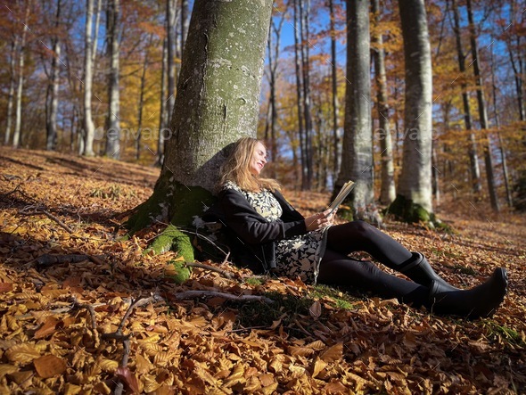 Young woman in the forest during autumn lying down under a tree and ...