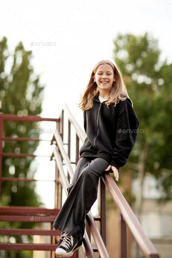 A teenage girl has fun and slides down the railing at the stadium Stock ...