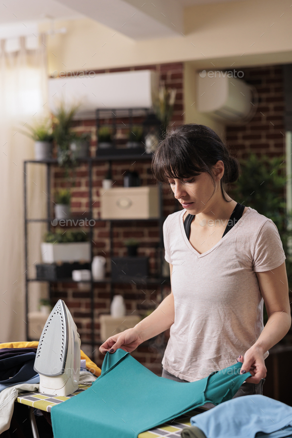Female domestic employee ironing clothes on ironing board Stock Photo ...