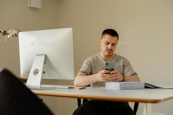 Young caucasian man sitting at his desk in the office and working with ...